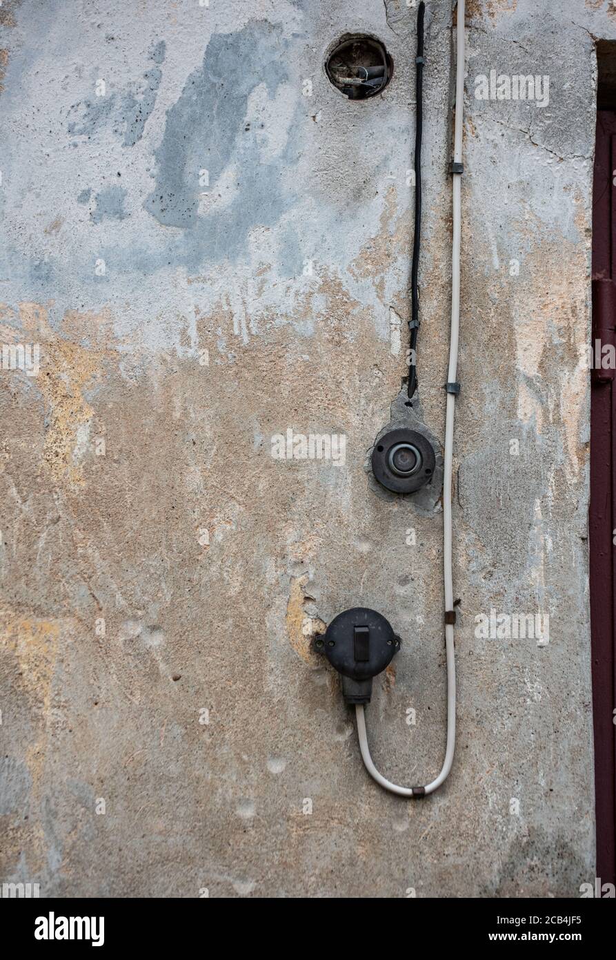 Close-up view of old broken entrance bell with old wires against wall ...