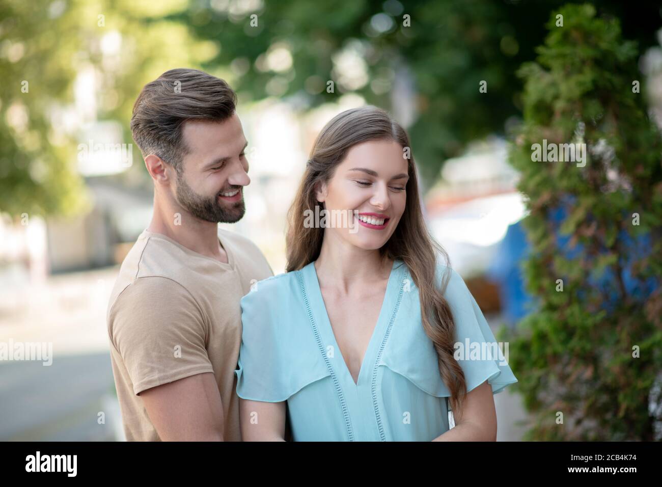 Bearded male hugging tenderly smiling female in blue dress Stock Photo ...