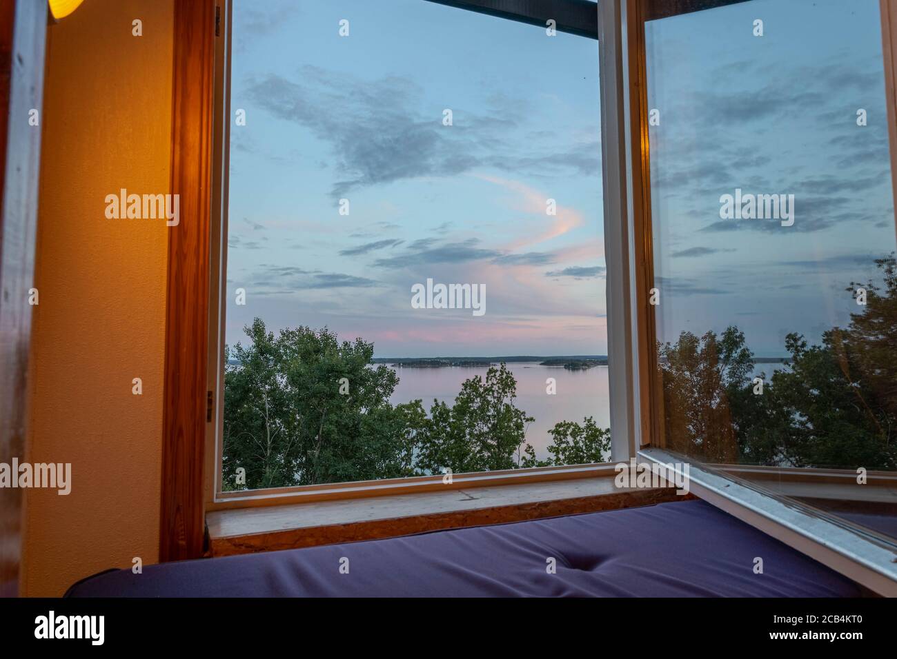 Beautiful summer sundown view from open window. Top of green trees on ...