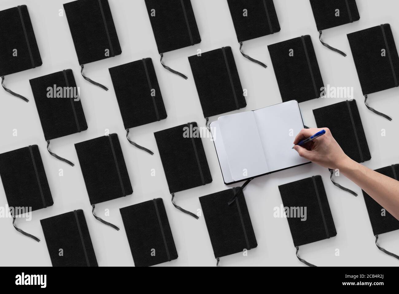 Flat lay of notebooks forming a texture. One of them is opened a hand ...