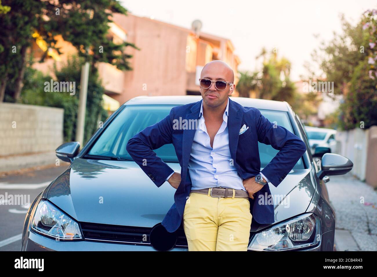 Successful handsome skeptical unhappy young man standing by his new car ...