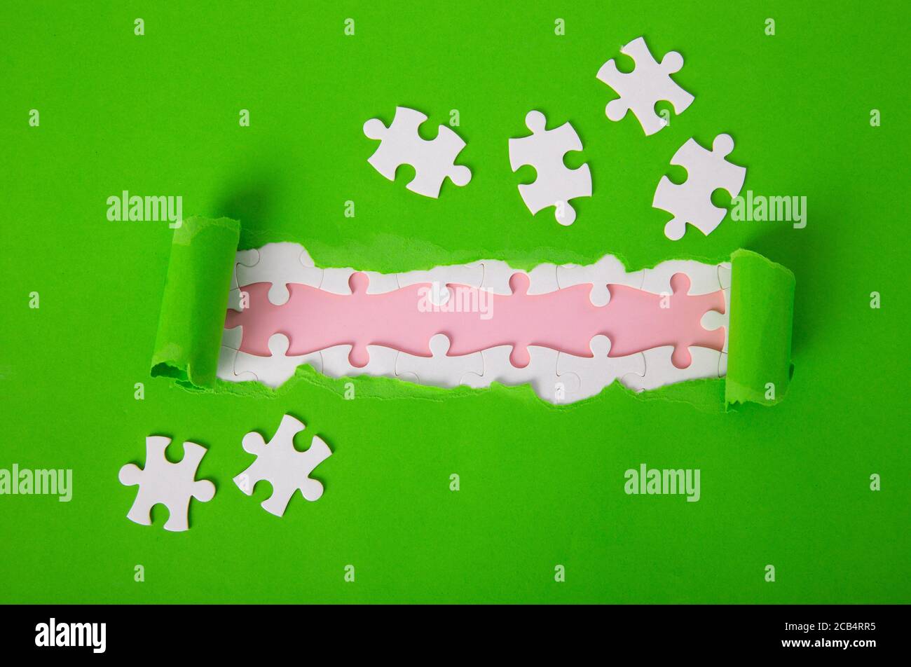 Top view closeup shot of a ripped paper with an incomplete white puzzle ...