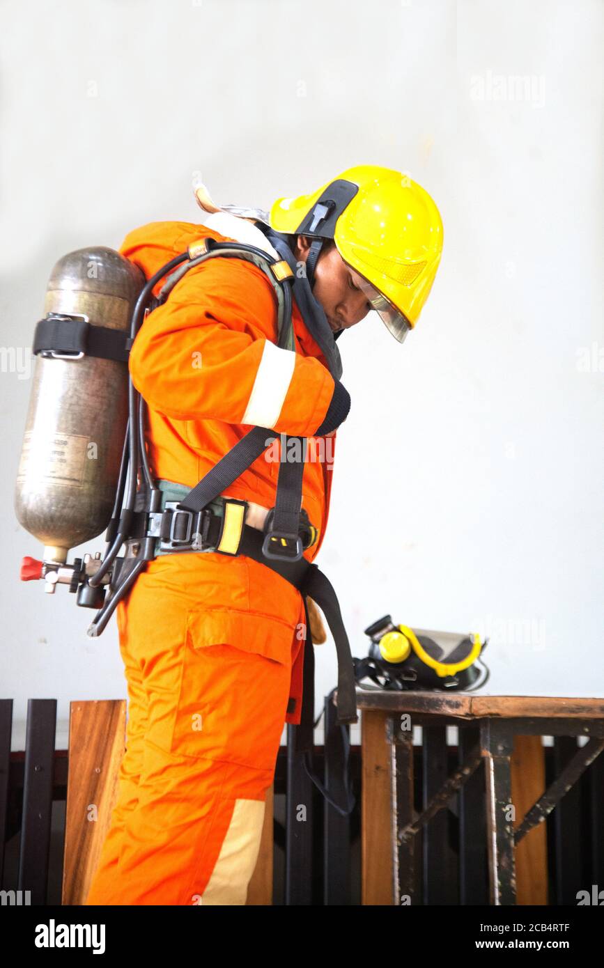 A portrait of Asian male firefighter in orange protective uniform, mask ...