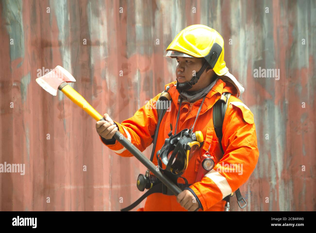 A portrait of Asian male fireman in orange protective clothing, mask ...