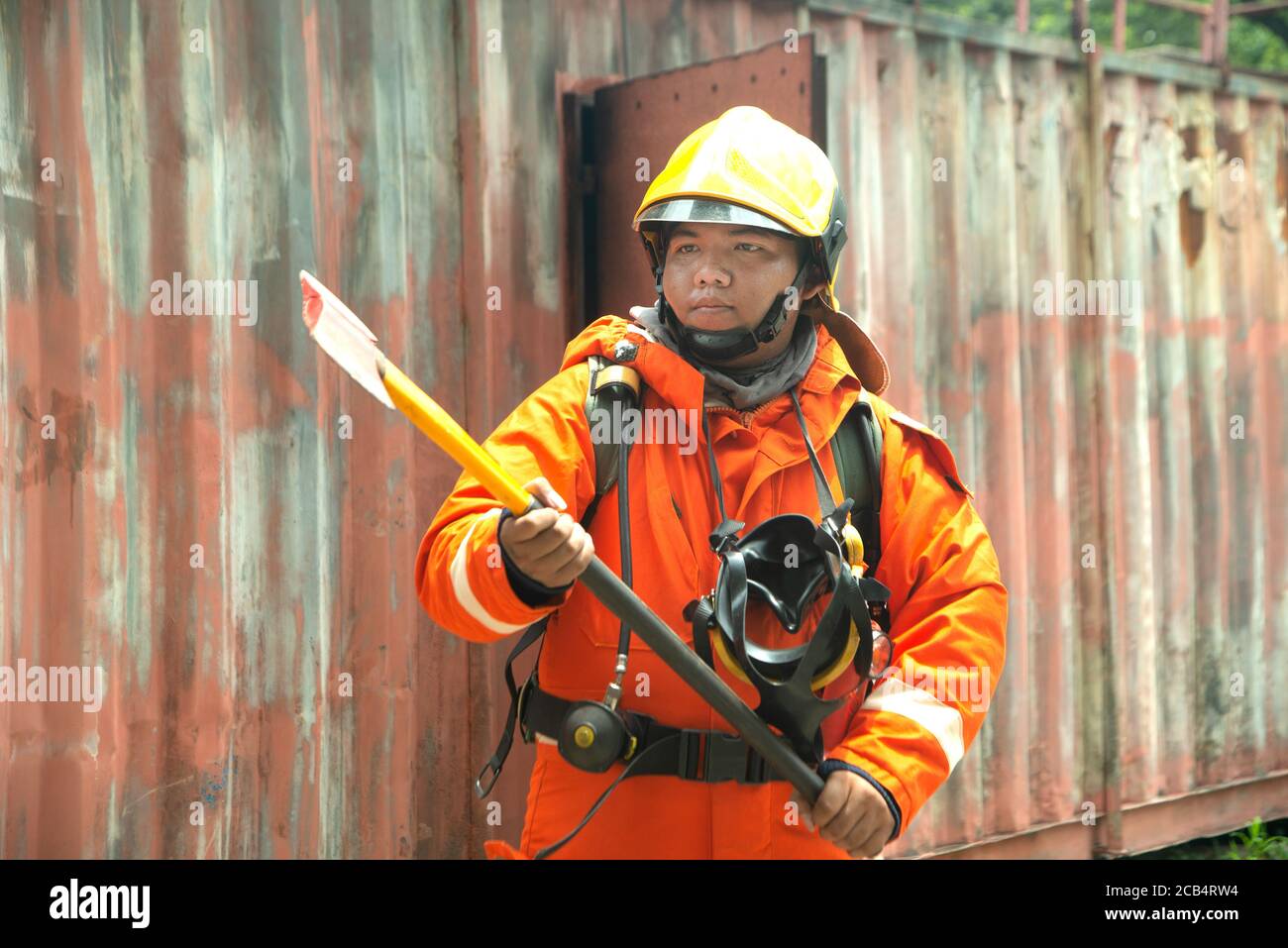 A portrait of Asian male fireman in orange protective clothing, mask ...
