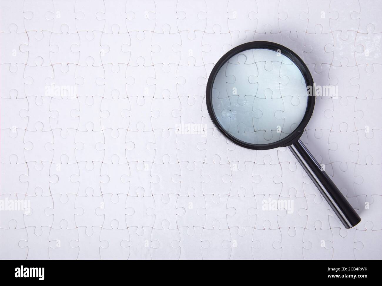 Top view closeup shot of a set of puzzle pieces with a magnifying glass ...
