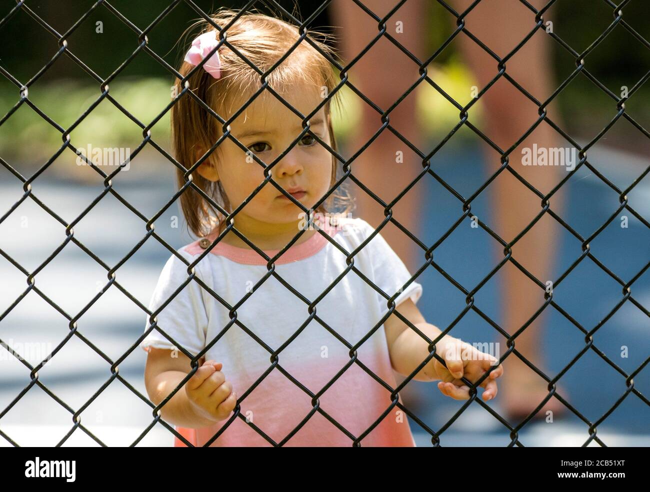Small child behind a mesh fence Stock Photo - Alamy