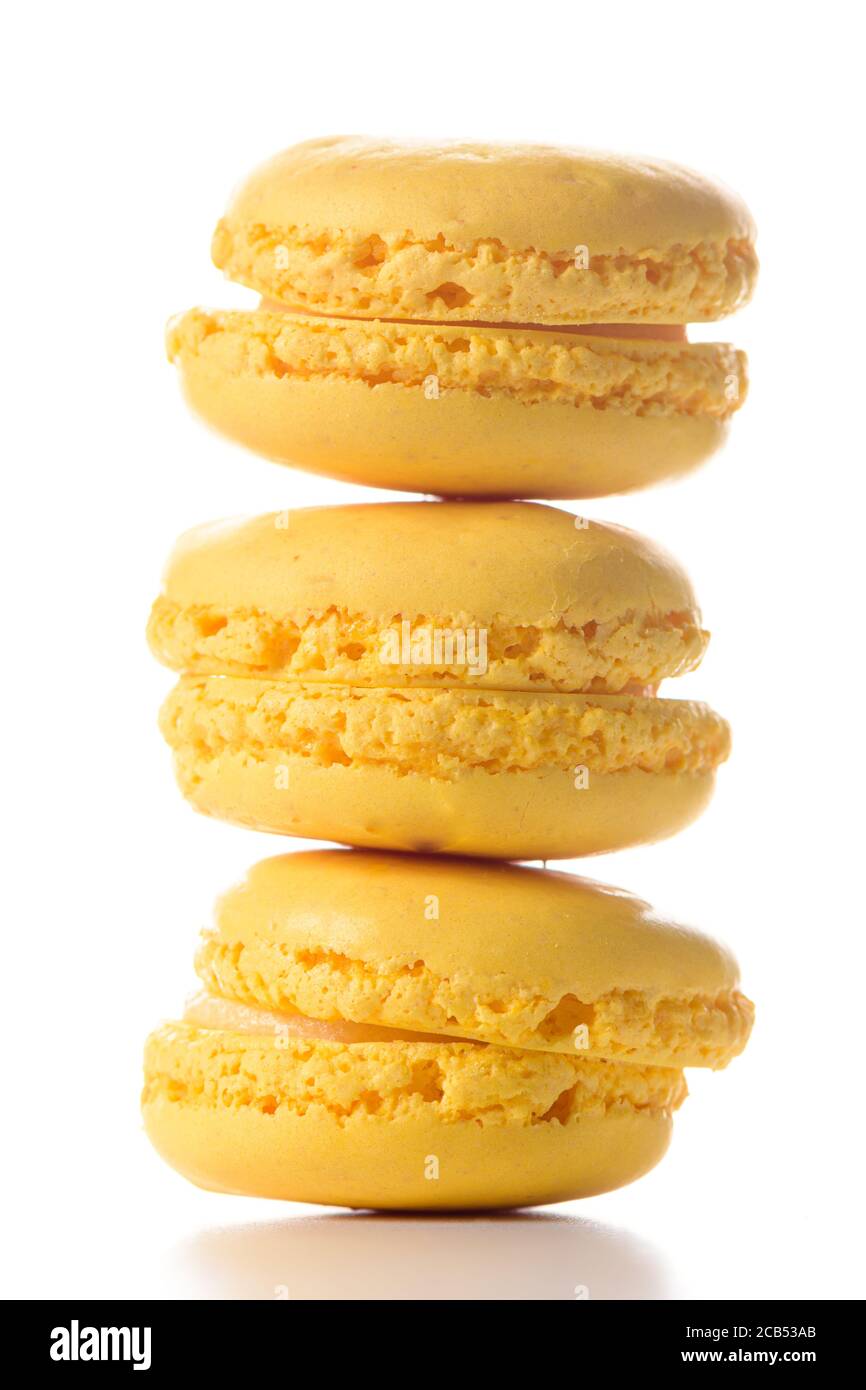 Three lemon flavoured macaroons standing on top of each other on white ...