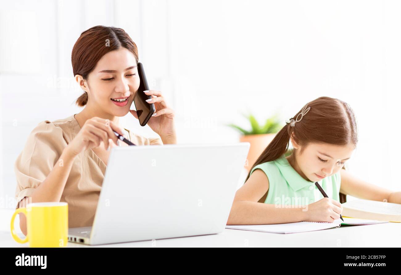 Mother working at home and teaching her daughter doing home work Stock ...