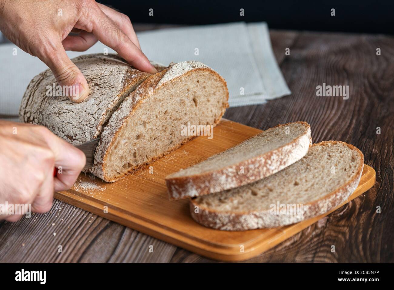 Close up of hands cutting a slice of rey bread. Male hands cutting ...