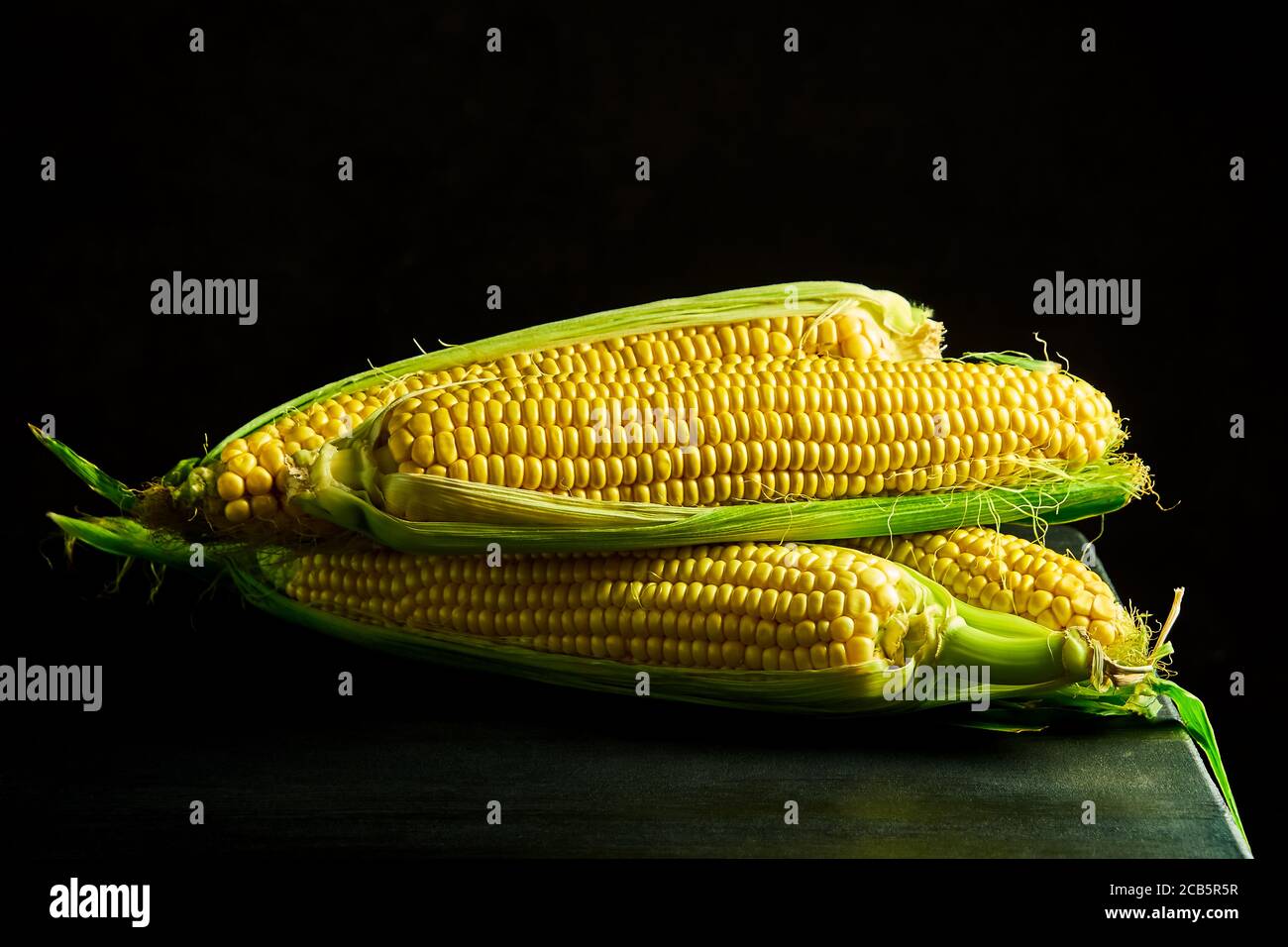 Cobs of ripe raw corn on a dark wooden table. healthy food, fresh raw ...