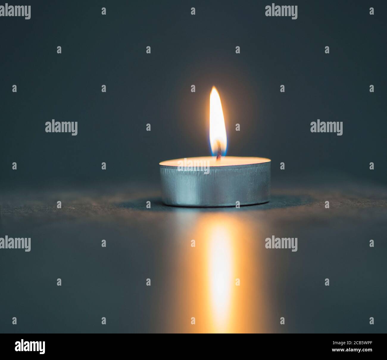 single tea light candle on the soft blurred grey background Stock Photo ...