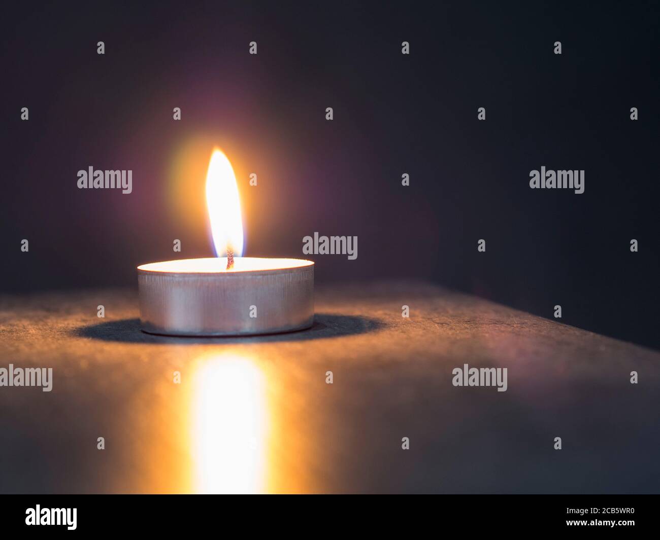 single tea light candle on the soft blurred grey background Stock Photo ...