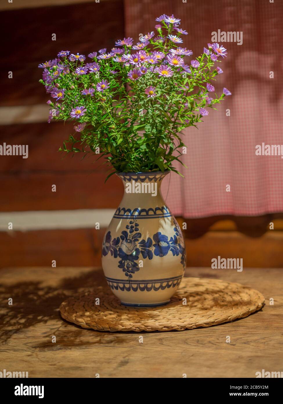 bunch of pink violet flowers in rustic ceramic painted vase on oak wood ...