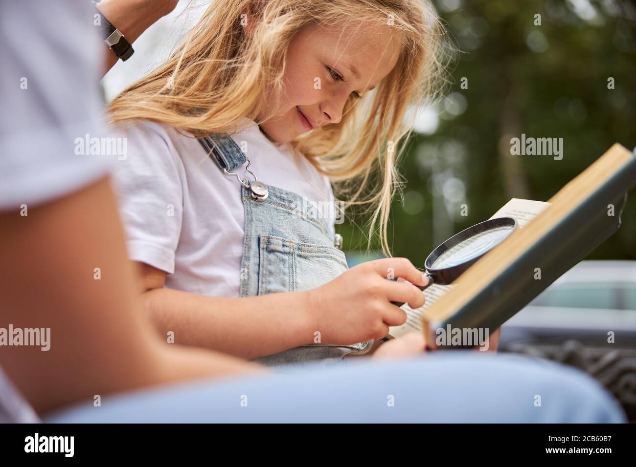 Pretty little school girl is doing homework in park Stock Photo - Alamy