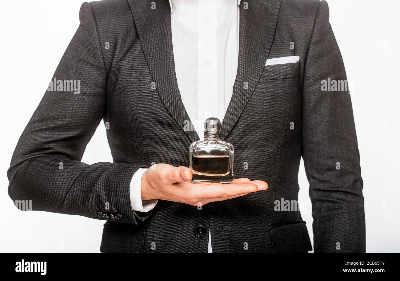 Man in a suit holding a bottle of perfume isolated on white background ...