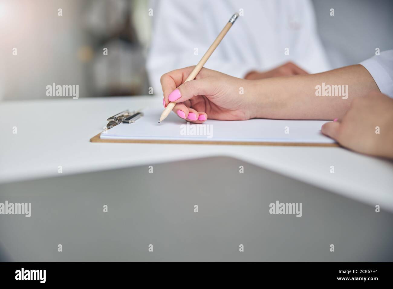 Female doctor taking notes about her patient Stock Photo - Alamy