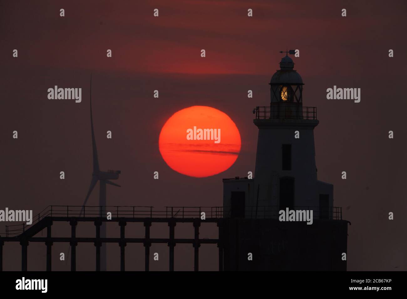 The sun rises behind Blyth East Pier Lighthouse in Northumberland Stock ...