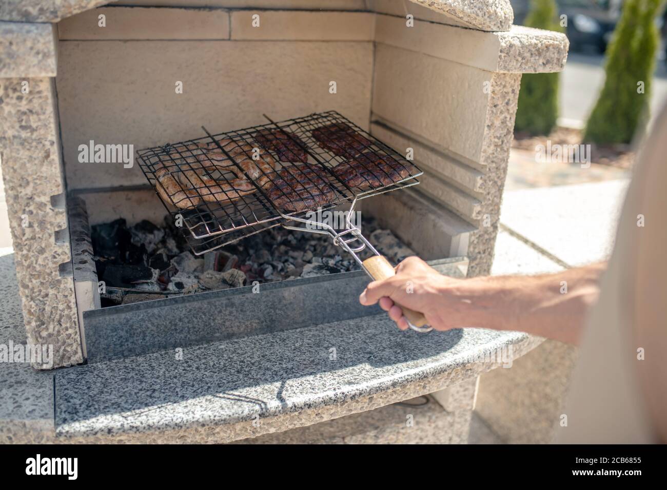 Close up picture of a mans hand holding grilled meat Stock Photo - Alamy