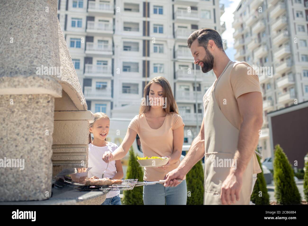 Dad grilling meat while his family watching Stock Photo - Alamy