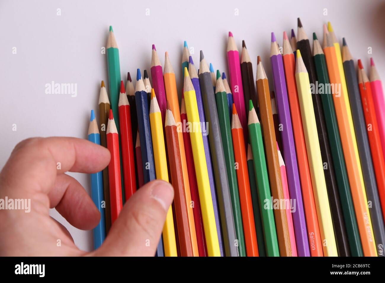 Closeup shot of a person picking colored pencils against a black ...