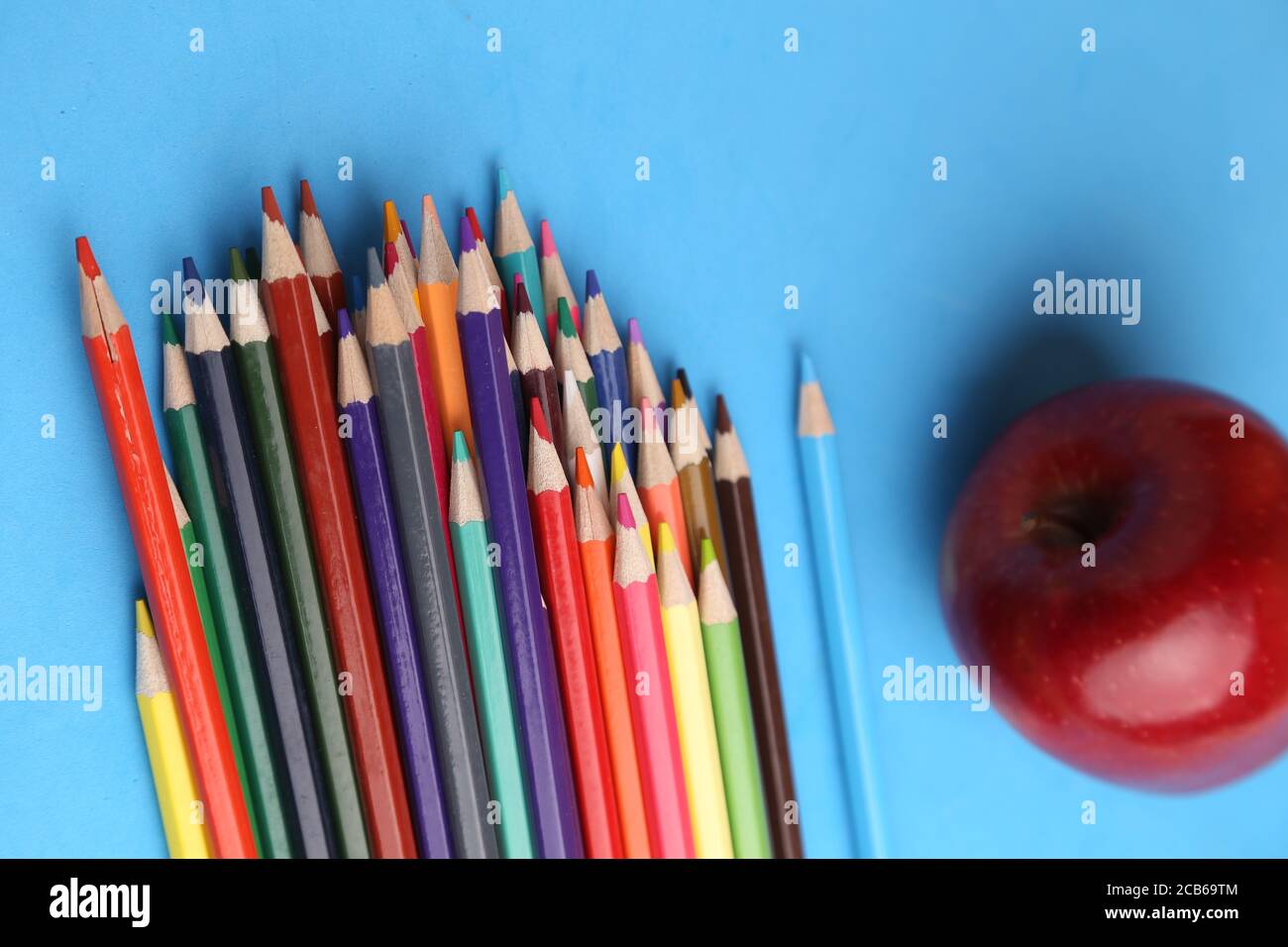 Top view of different colored pencils on a blue surface with a red ...