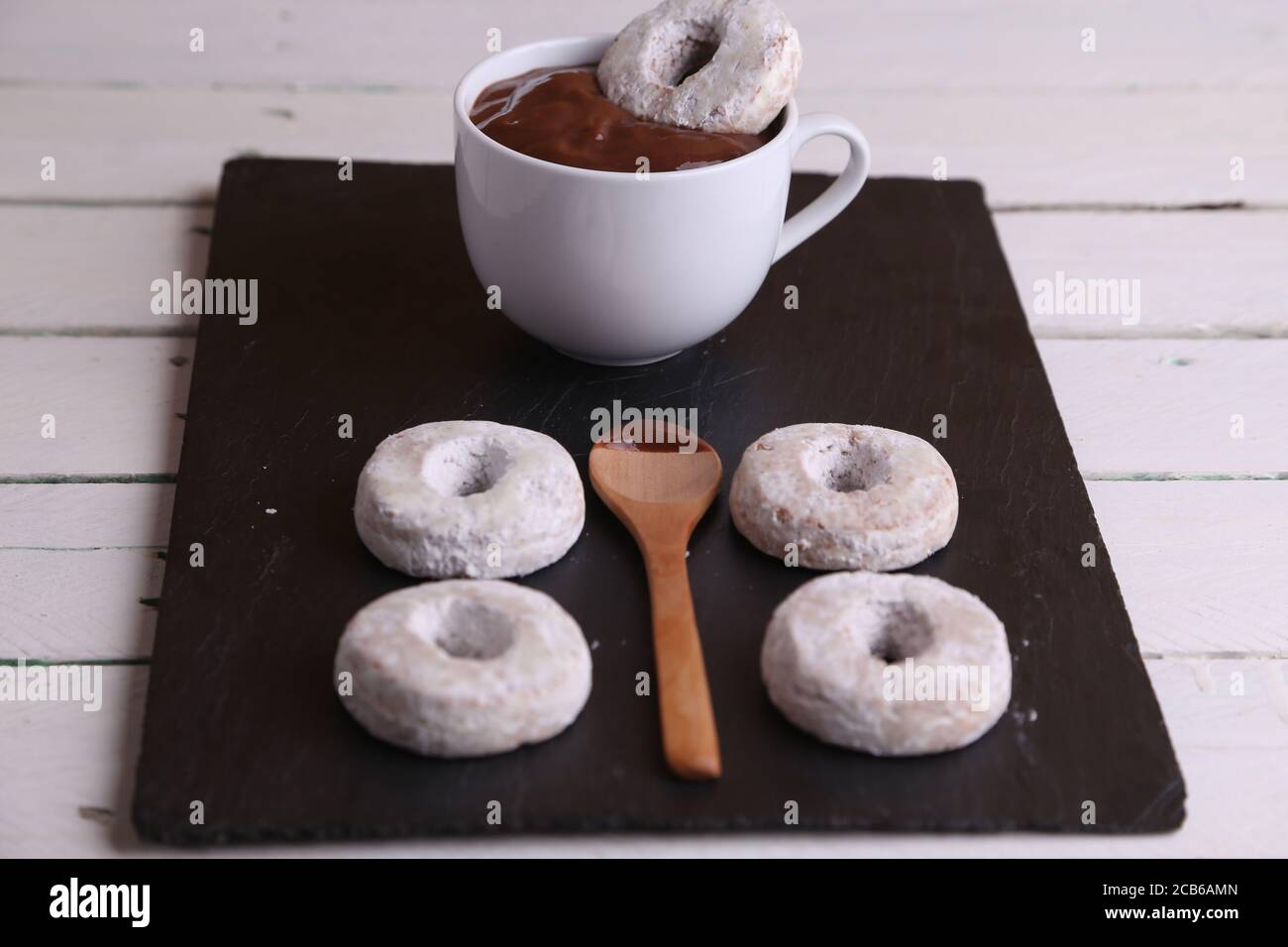 Cup of melted chocolate and the sweet doughnuts covered in sugar powder ...