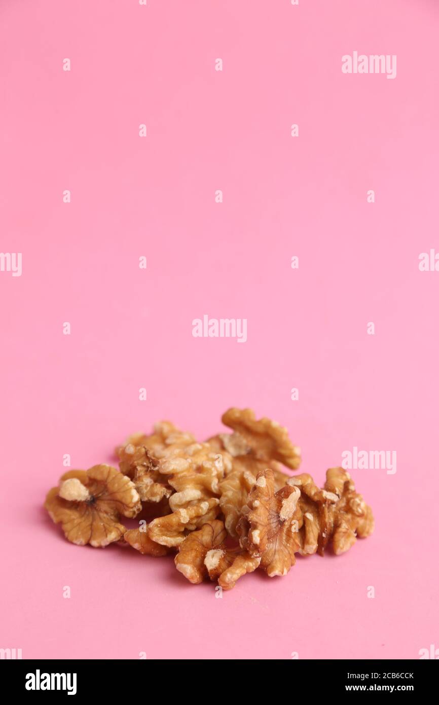 Vertical shot of a bunch of walnuts on a pink background Stock Photo ...
