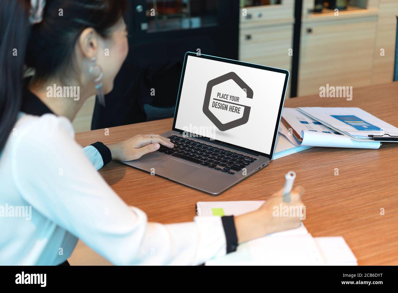 Side view of businesswoman working on mock up laptop and paperwork on ...