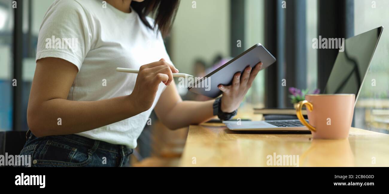 Side view of female university student doing assignment with digital ...