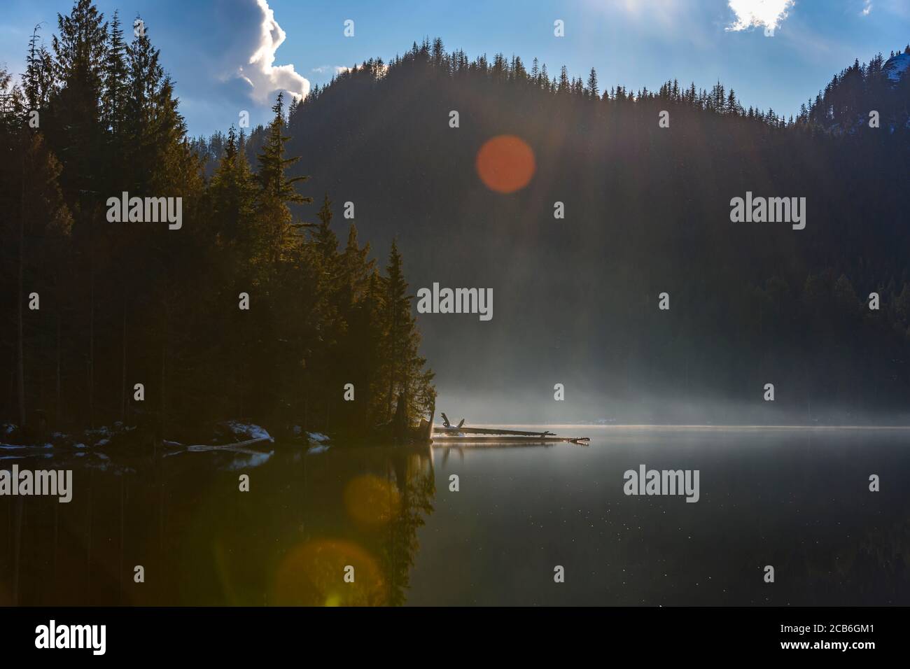 Beautiful lake with surrounding mountains . Sunny, blue sky. Snow on ...