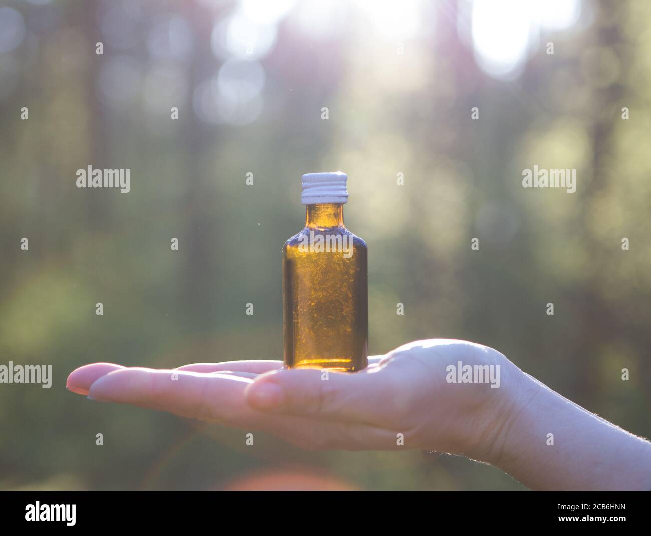 Hand holding essential oil, brown bottle Stock Photo - Alamy