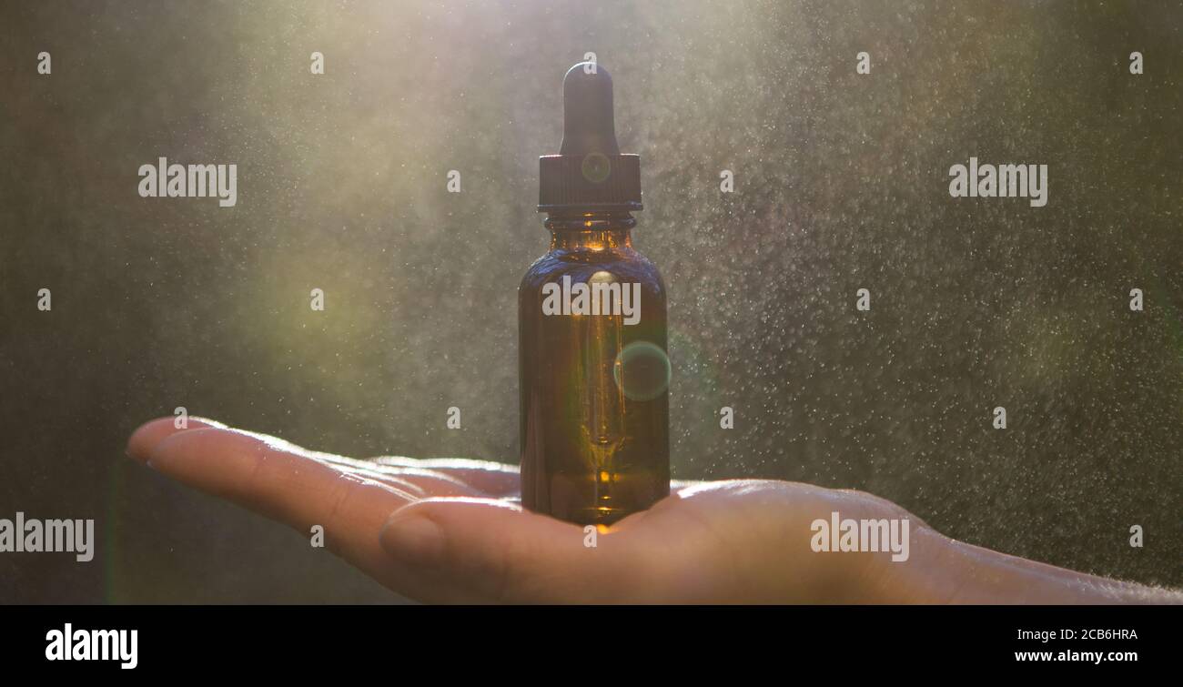 Hand holding essential oil, bottle - blurred background Stock Photo - Alamy
