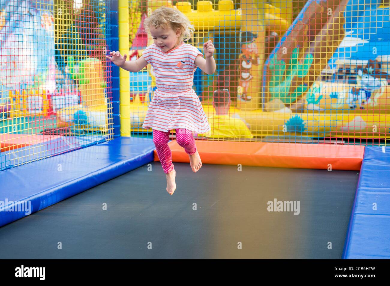 Cute blonde girl jumping on big trampoline at outdoor playground Stock ...