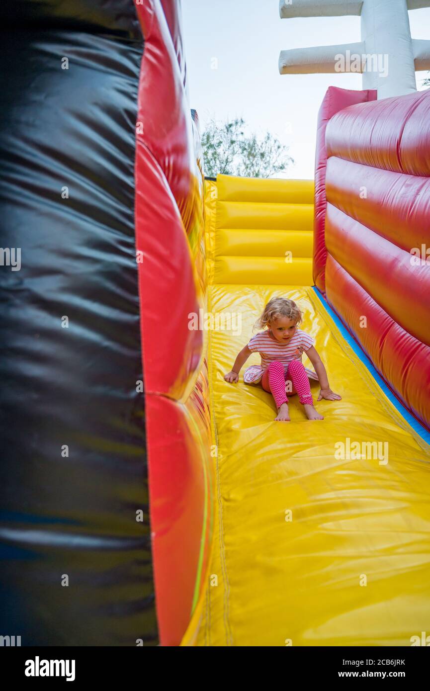 Cute blonde girl riding an inflatable slide Stock Photo - Alamy