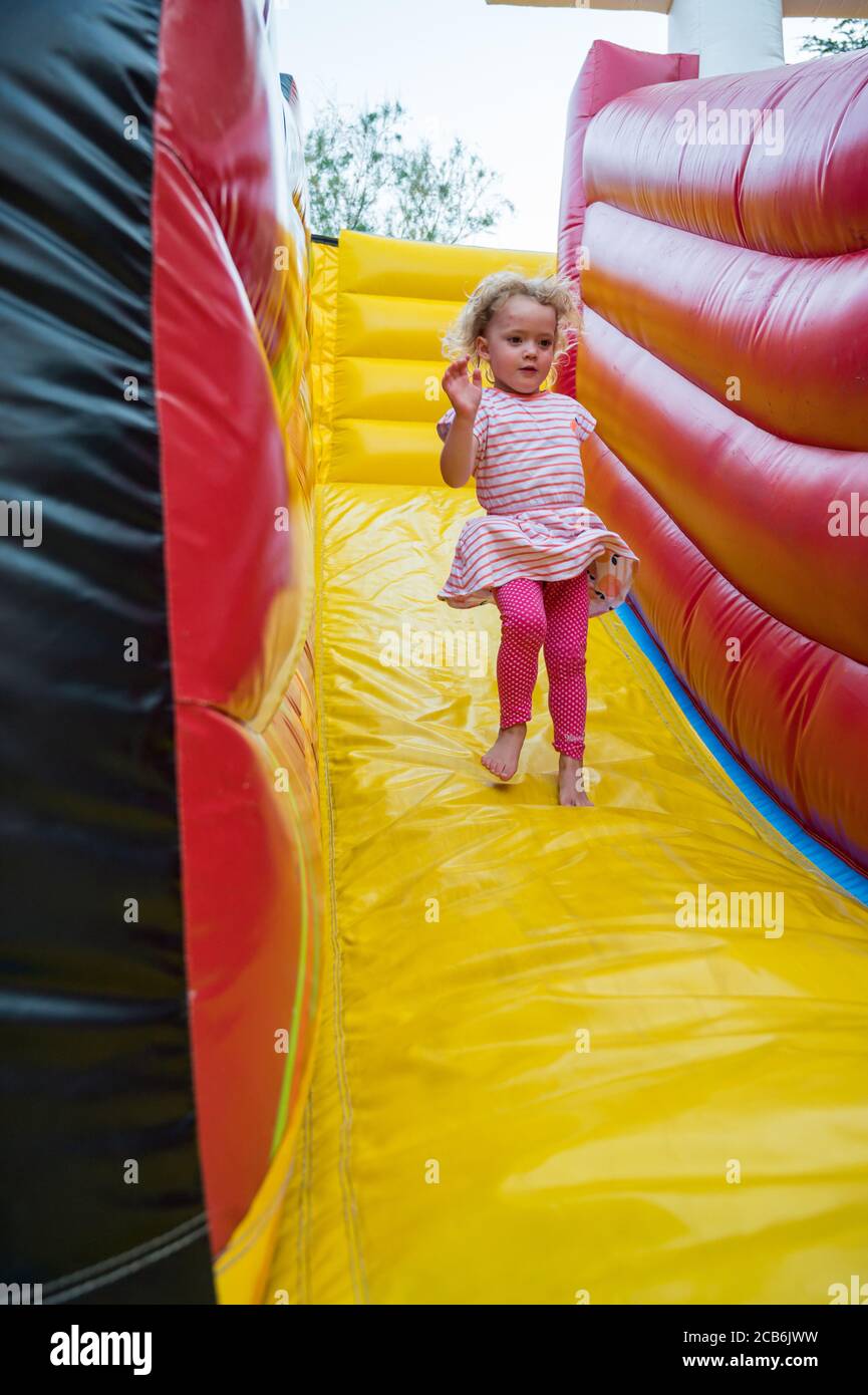 Cute blonde girl riding an inflatable slide Stock Photo - Alamy