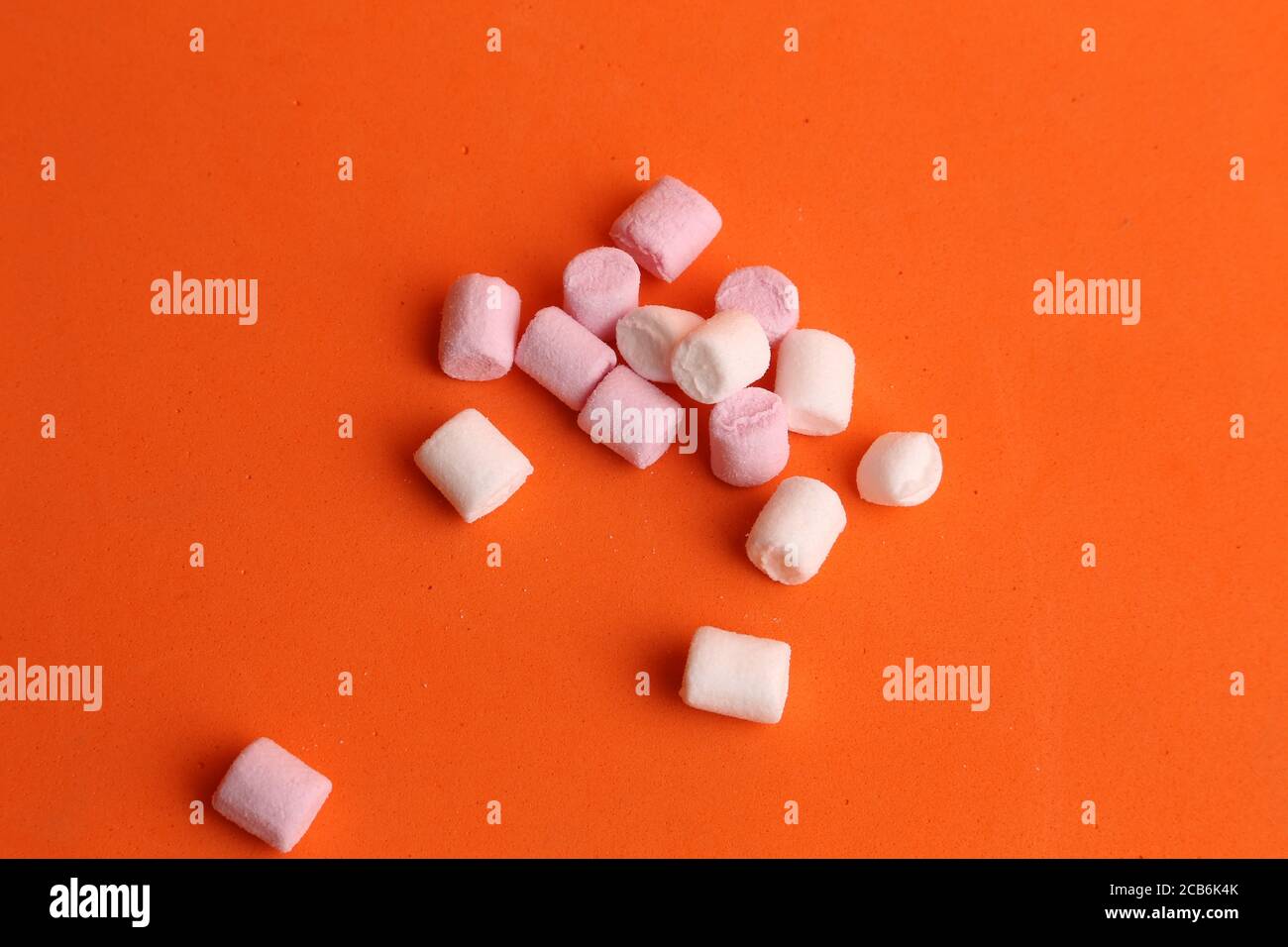 High angle shot of a pile of marshmallows isolated on an orange surface ...