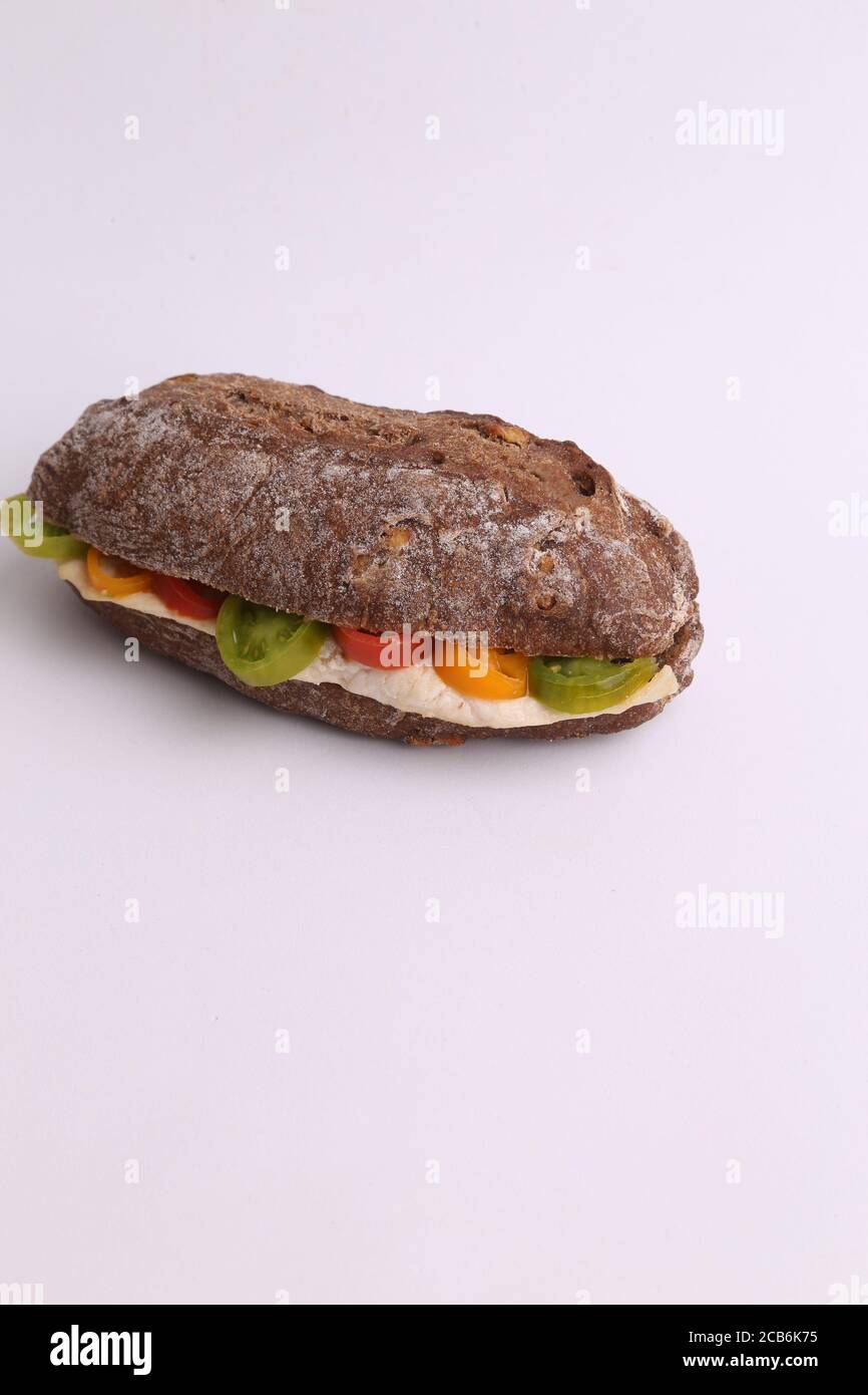 Vertical closeup of a deliciously loaded sandwich on a white surface ...