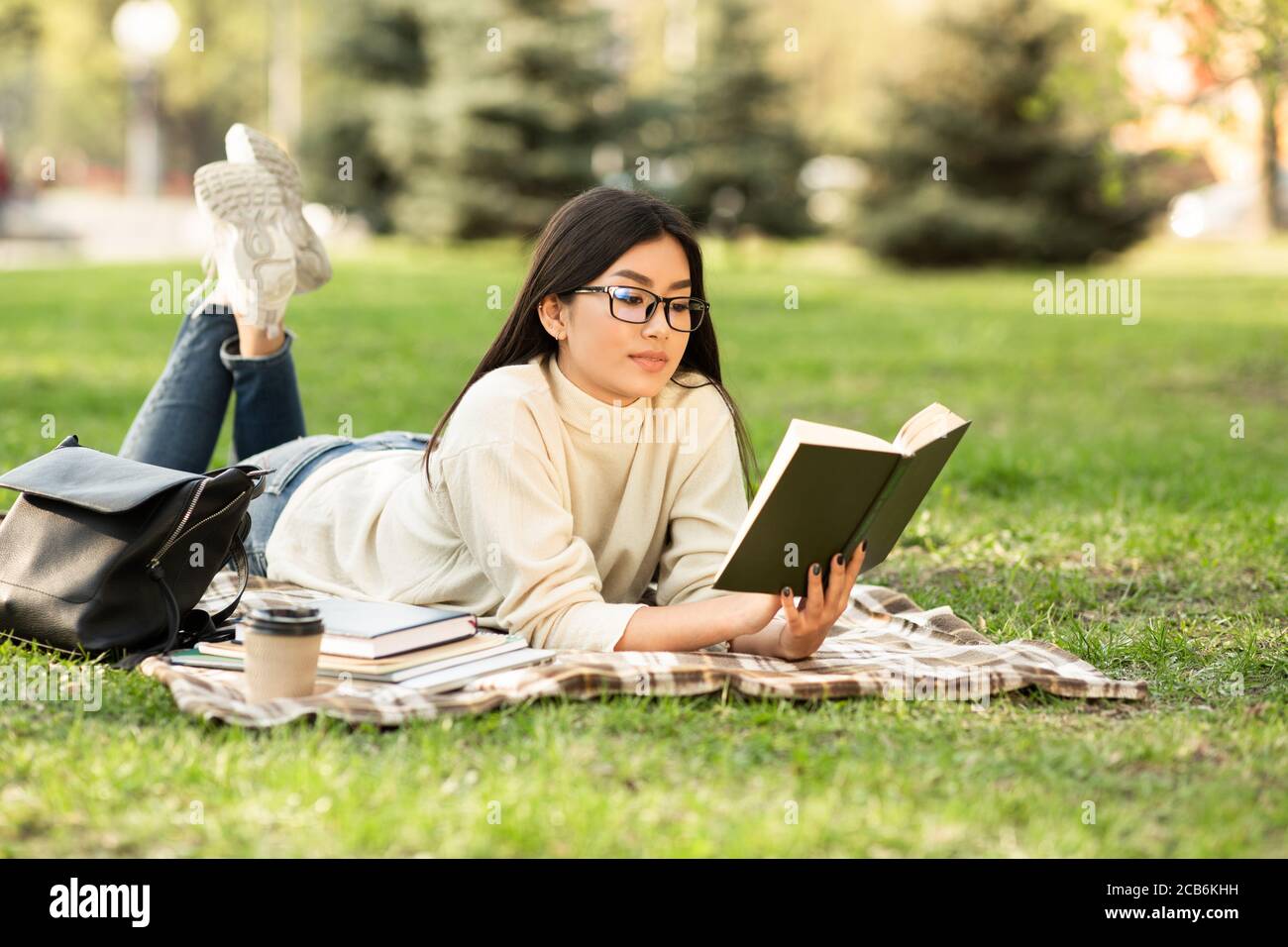 Girl reading a novel lying on the grass Stock Photo - Alamy