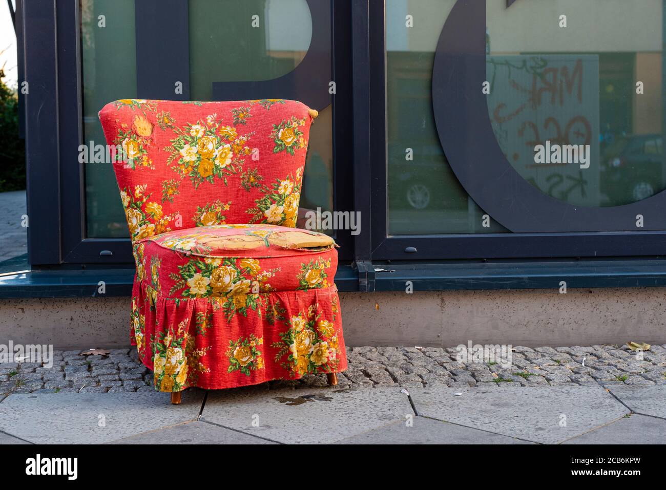 Old scruffy red armchair on a sidewalk Stock Photo - Alamy
