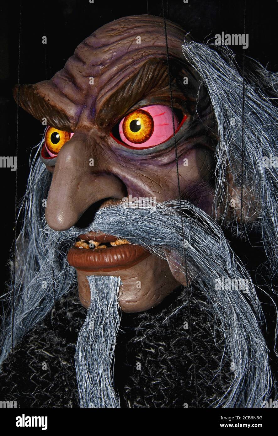 Wooden wizard puppet with pink and yellow bloodshot eyes, rotting teeth ...