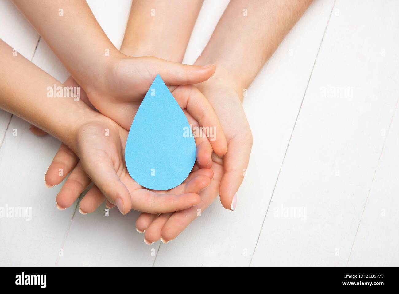 Human hands holding water drop isolated on white wooden background. Top ...