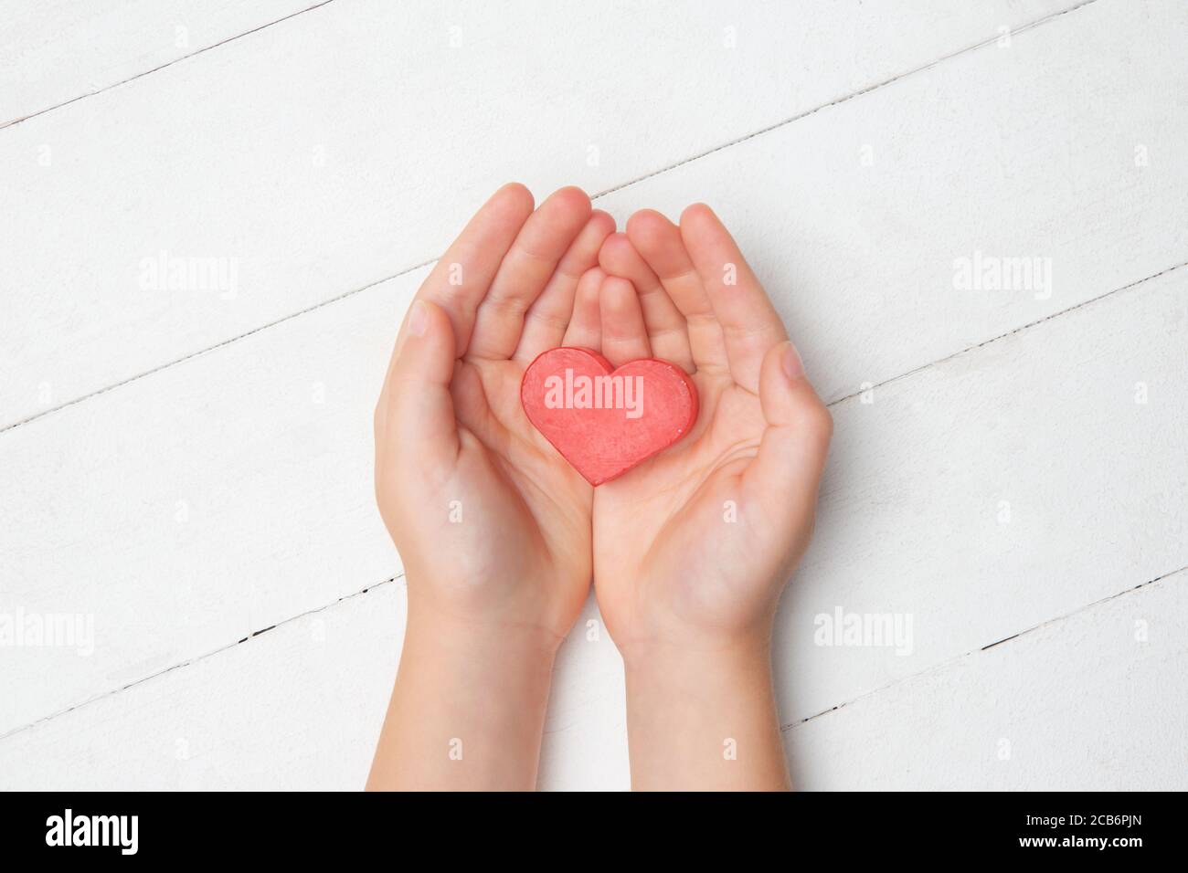 Human hands holding, giving heart isolated on white wooden background ...