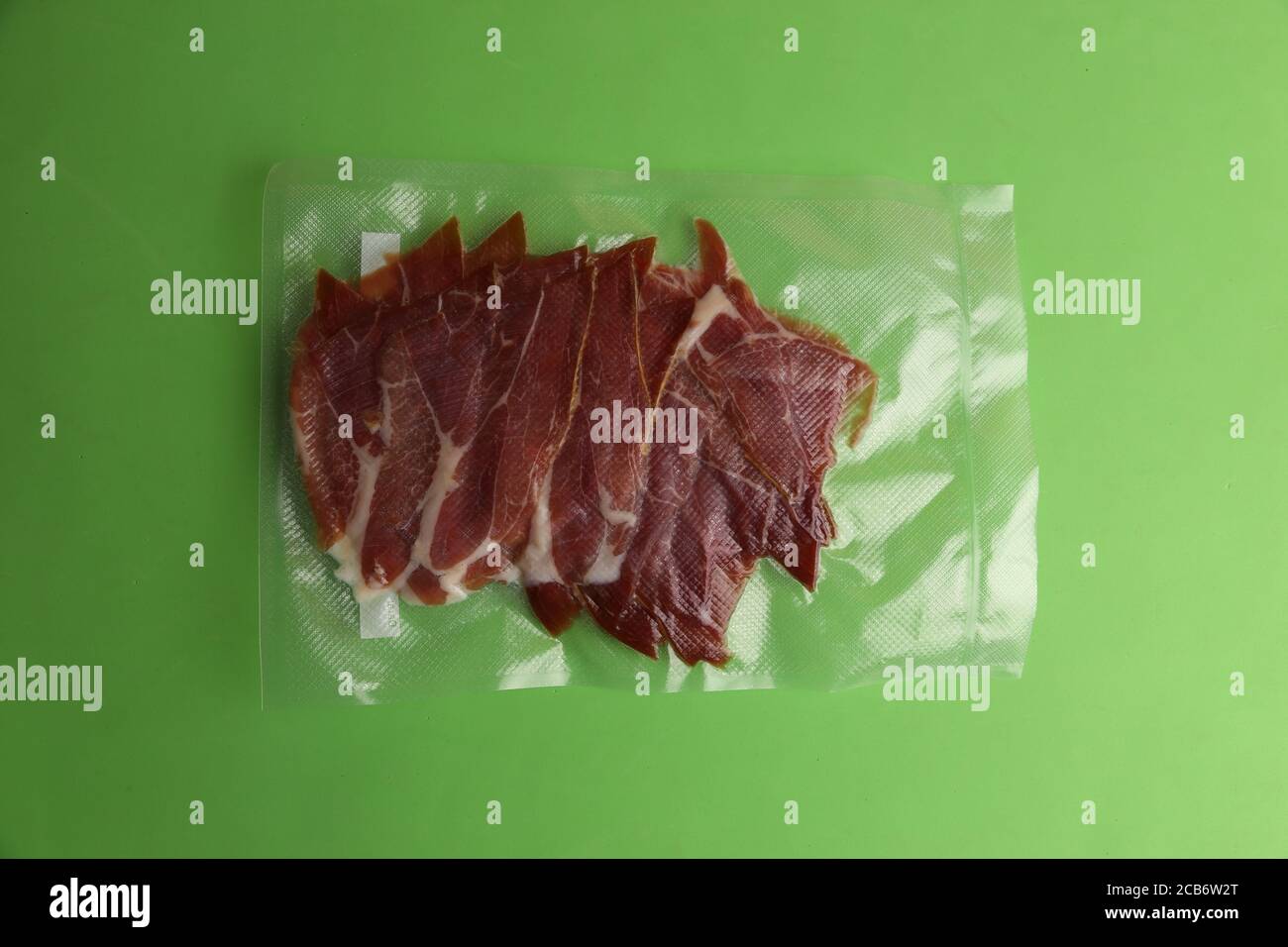 Overhead shot of raw meat slices in vacuum packaging on a green ...