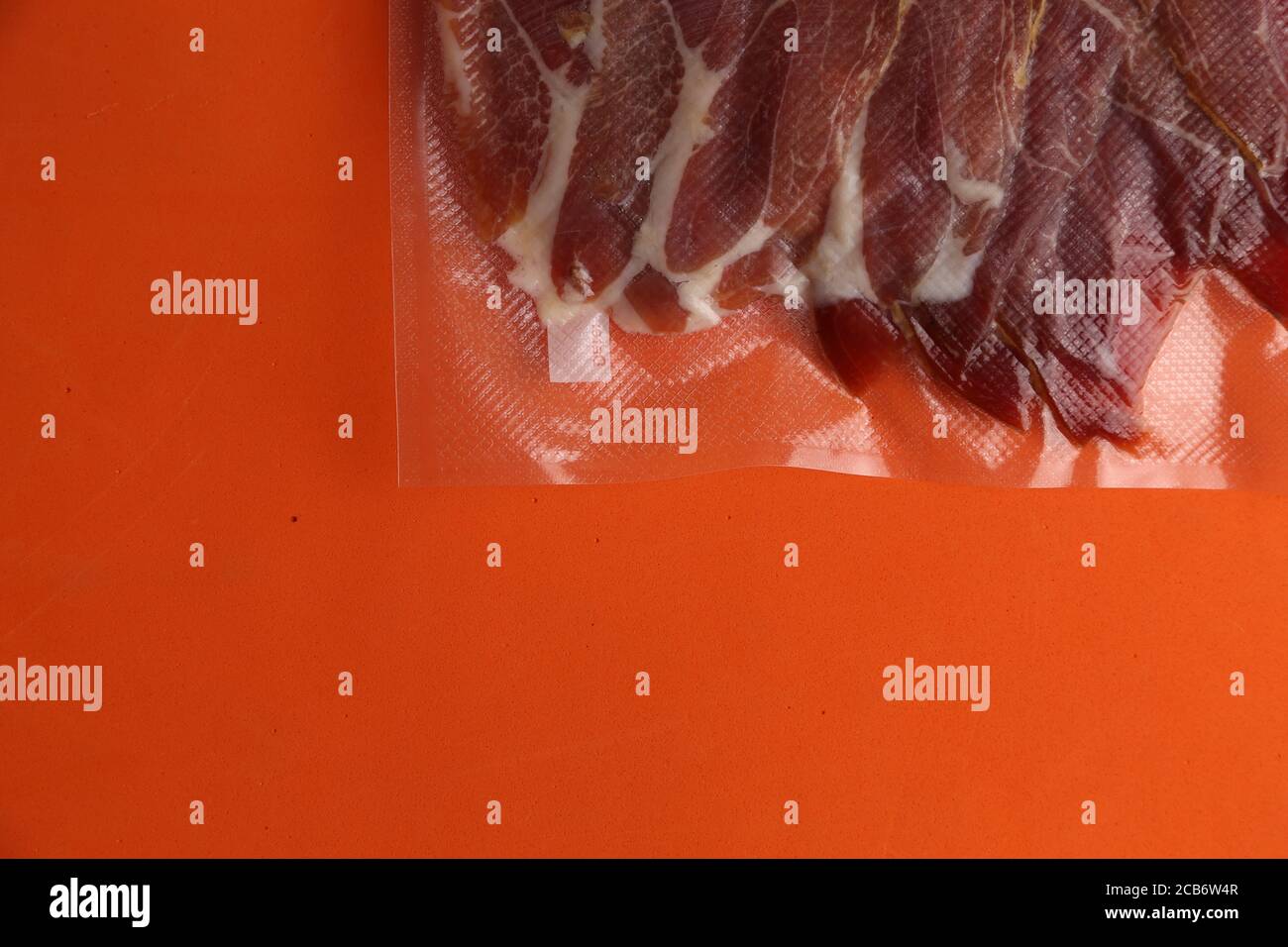 High angle shot of raw meat in a plastic bag isolated on an orange ...