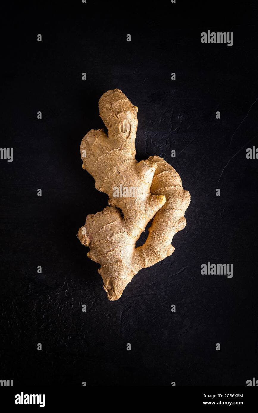 Beautiful whole curved ginger root in the centre of textured black ...