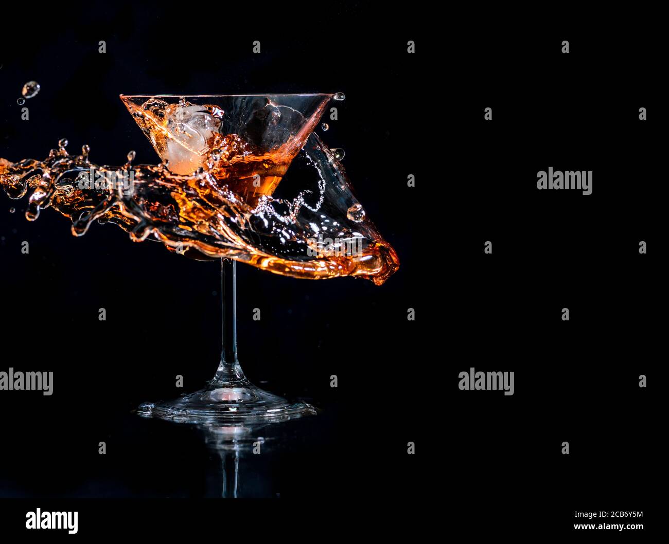 Cocktail splash in martini glass over black background with copyspace ...