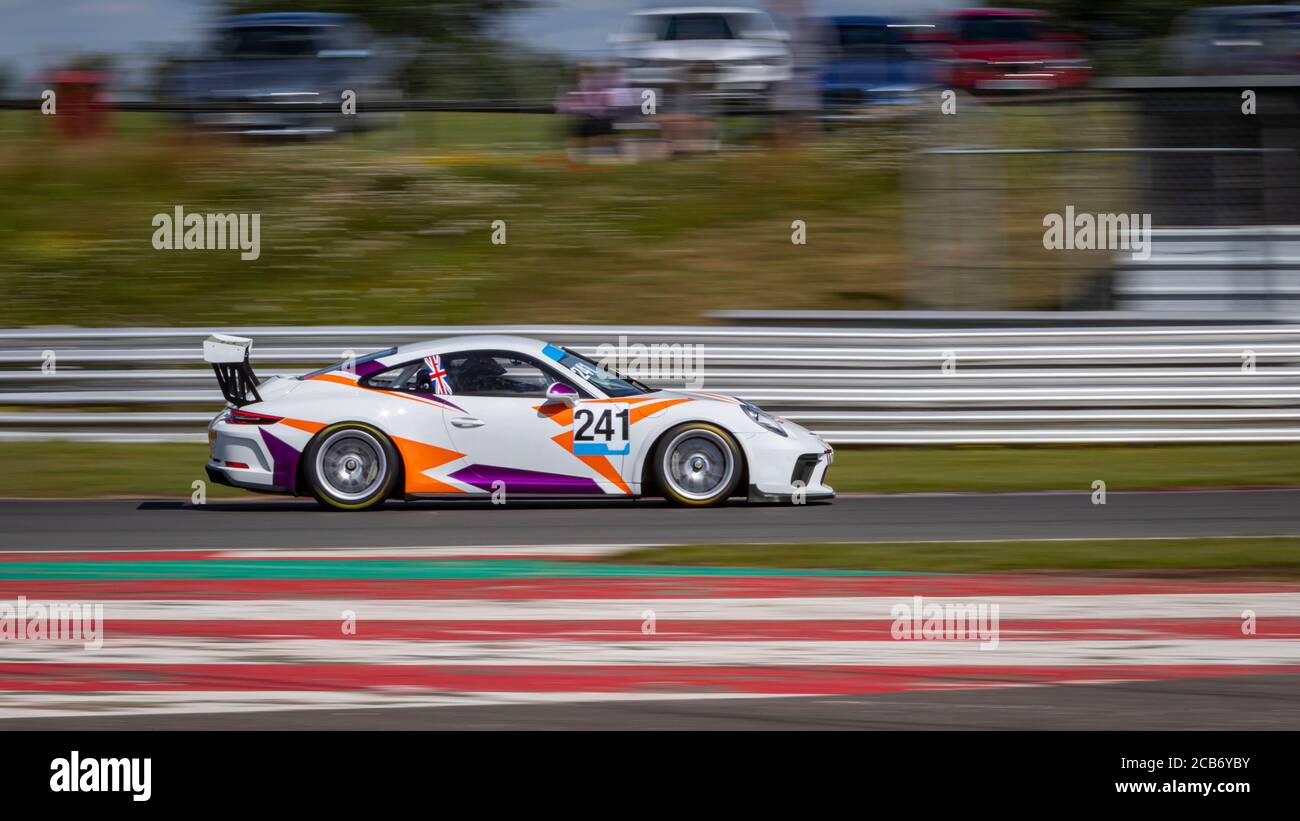 A panning shot of a white, orange and purple racing car as it circuits ...