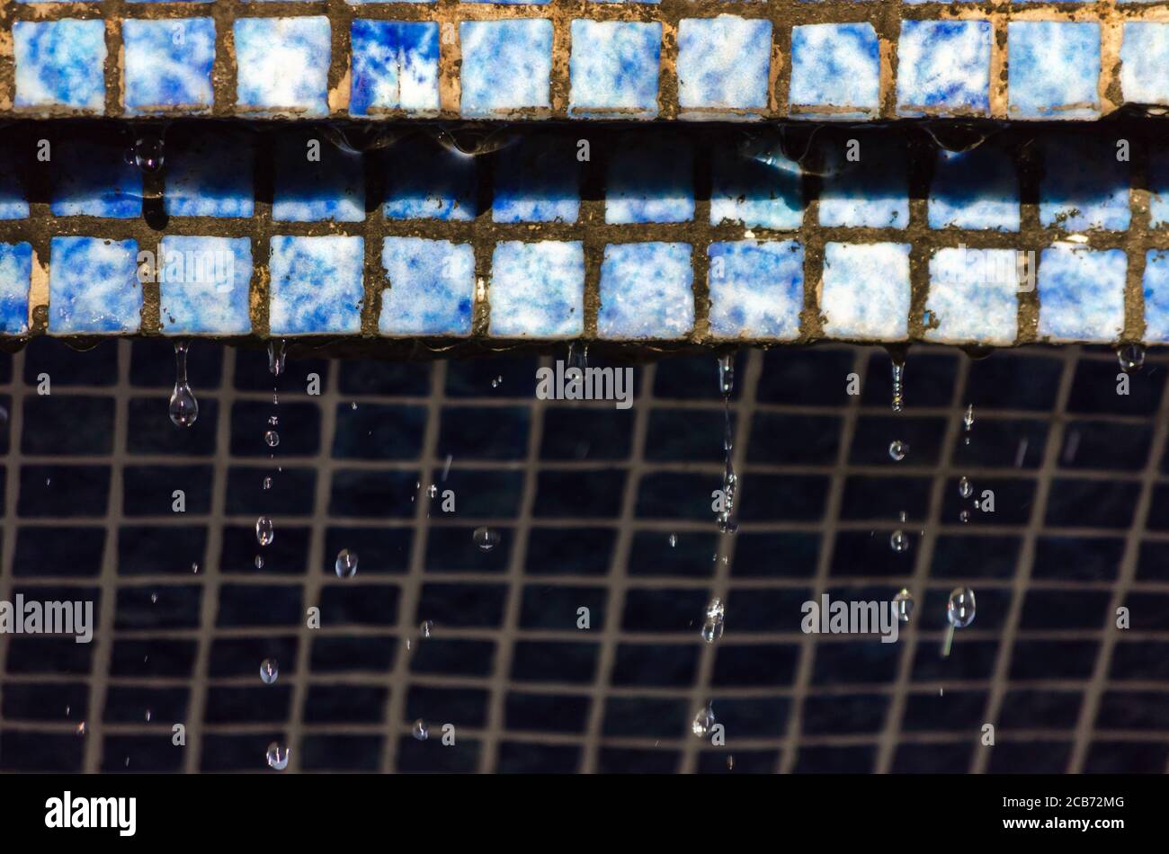falling water drops from wall with vintage tiles close up abstract ...