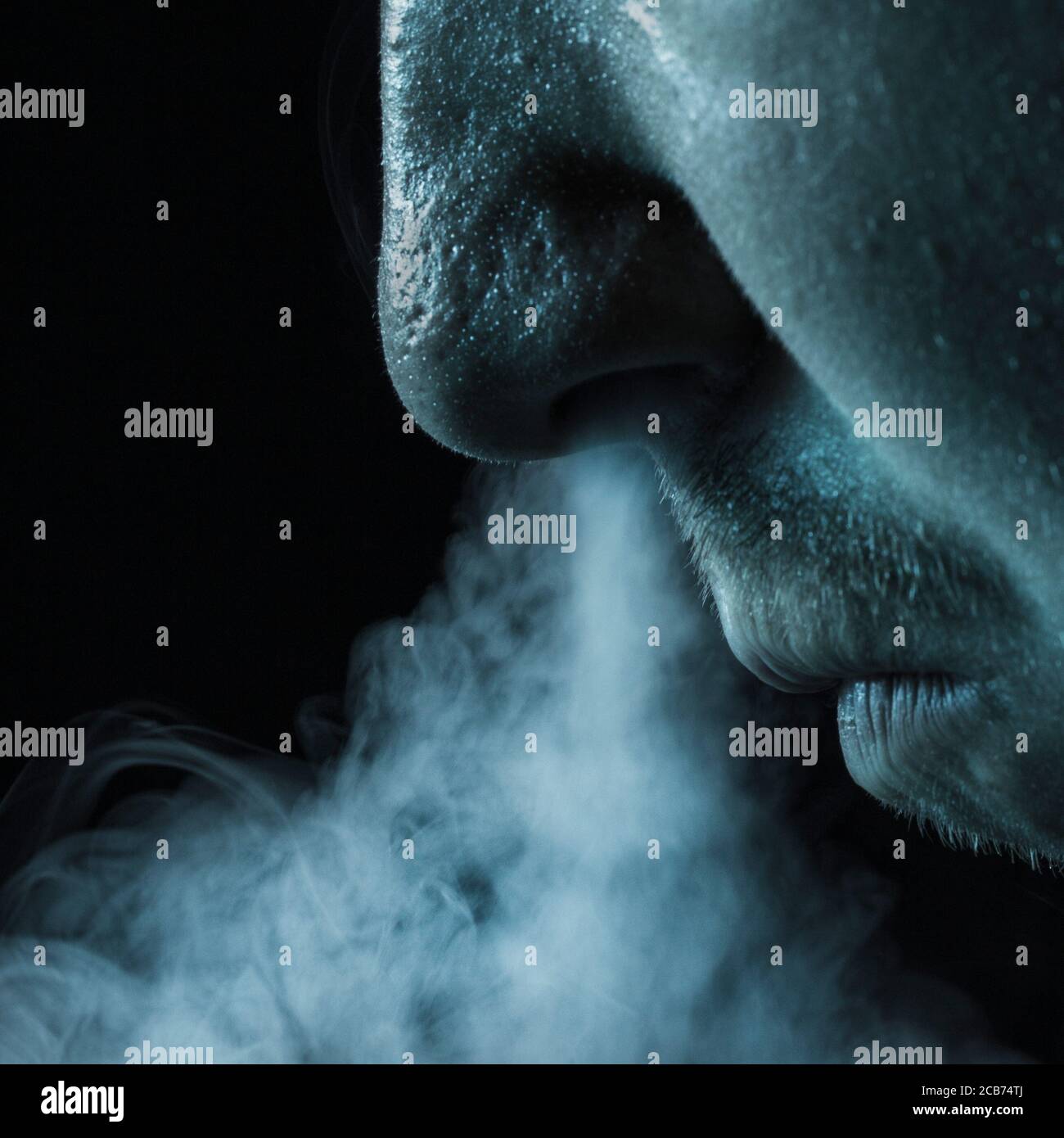 part of face and running cigarette smoke from nose closeup on dark ...